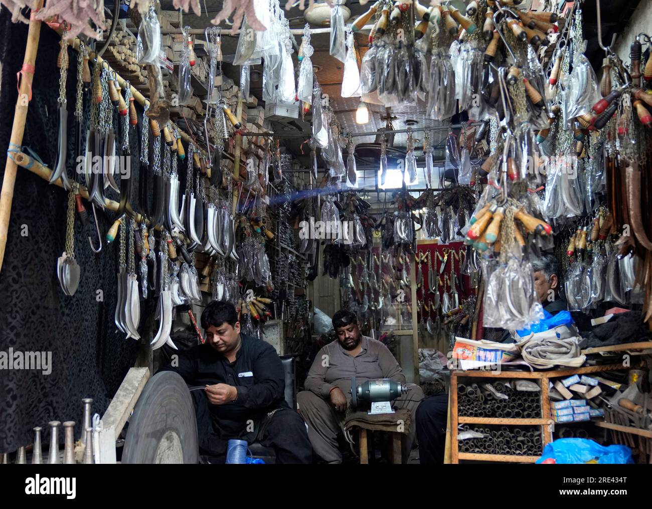 Pakistani iron smiths sharpen knives, as bunches of knives and chains ...