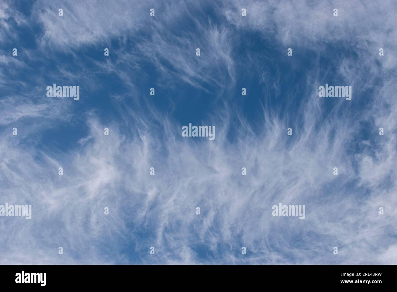 Thin, wispy streaks of cirrus clouds overhead in blue sky. Formed by ...