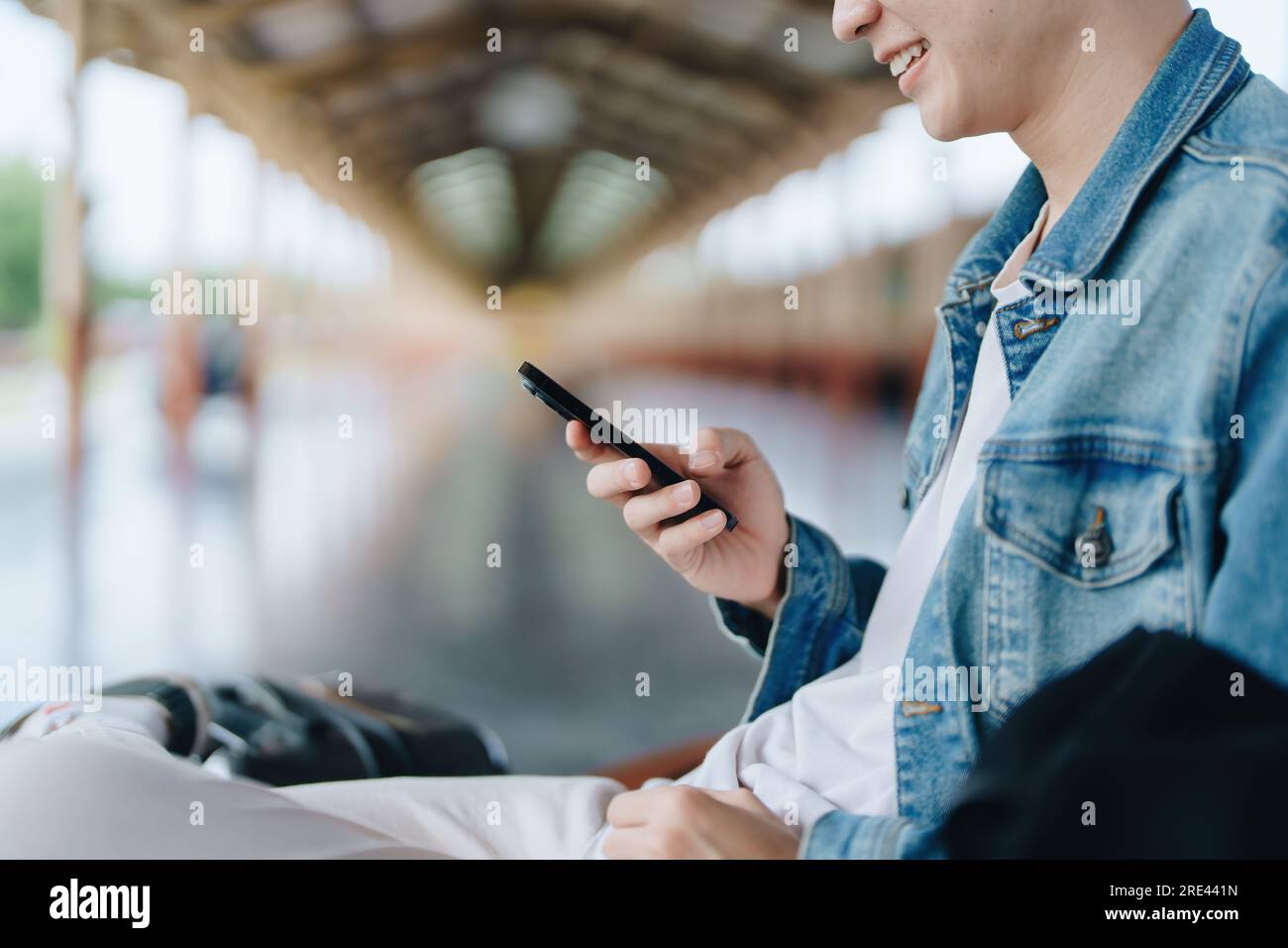 Asian teenage male traveler using her smart phone mobile while waiting ...