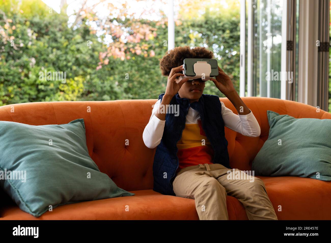 Happy african american boy sitting on sofa using vr headset Stock Photo ...