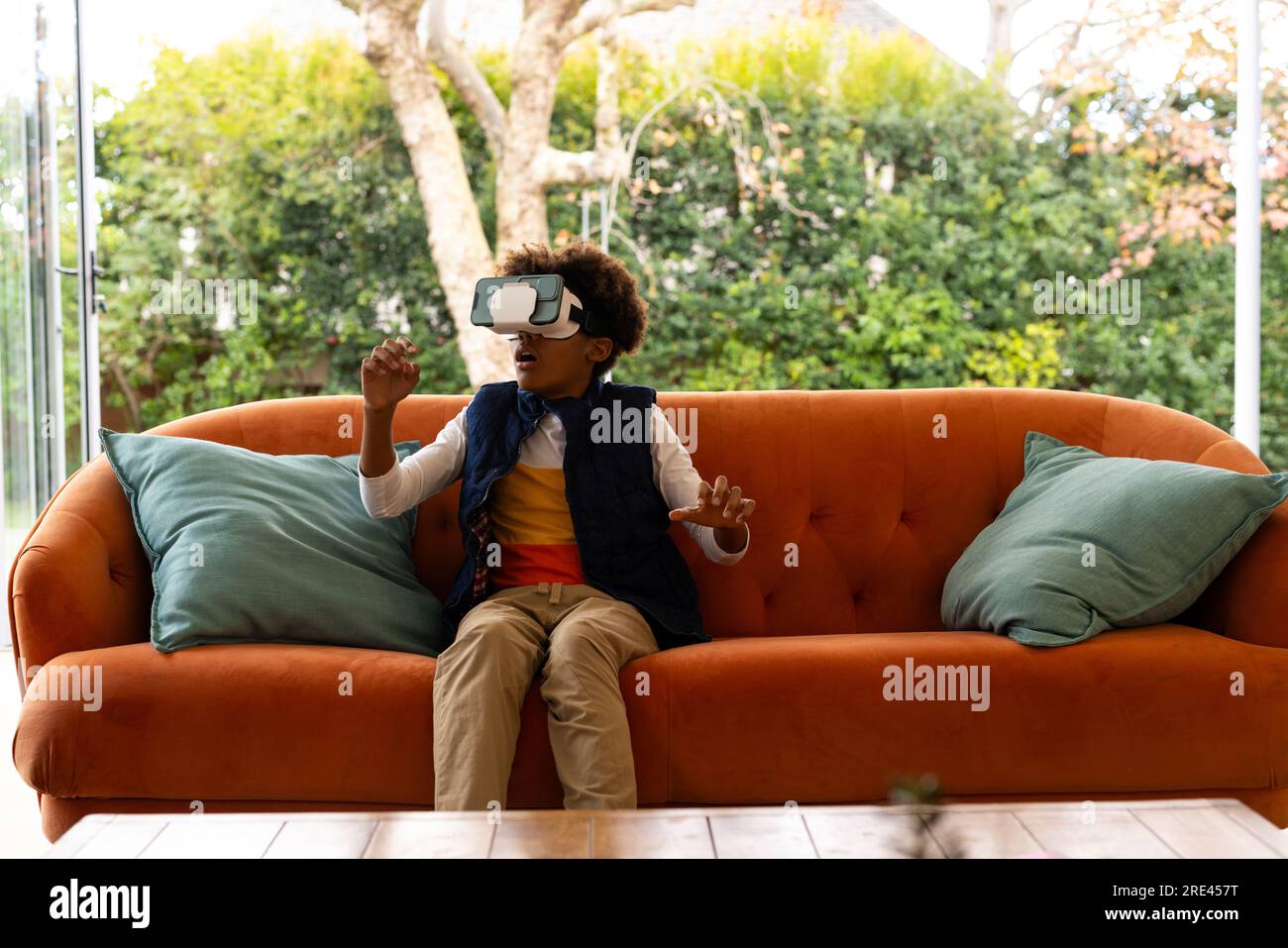 Happy african american boy sitting on sofa using vr headset and ...