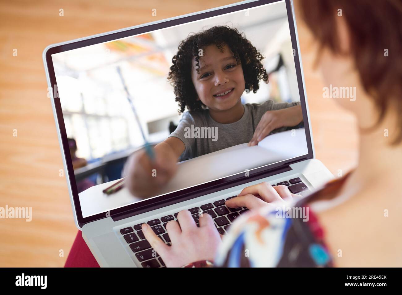 Rear view of caucasian girl using laptop while having a video call with a biracial boy at school ...