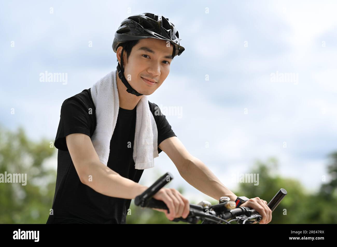 Asian man cyclist in sport clothes and helmet biking in the public park ...