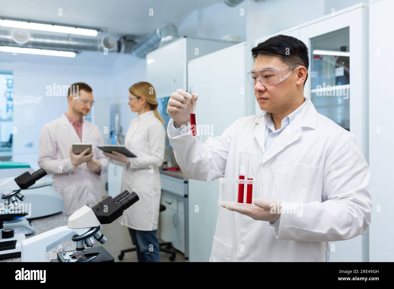 Serious asian scientist inside laboratory researching blood in test ...