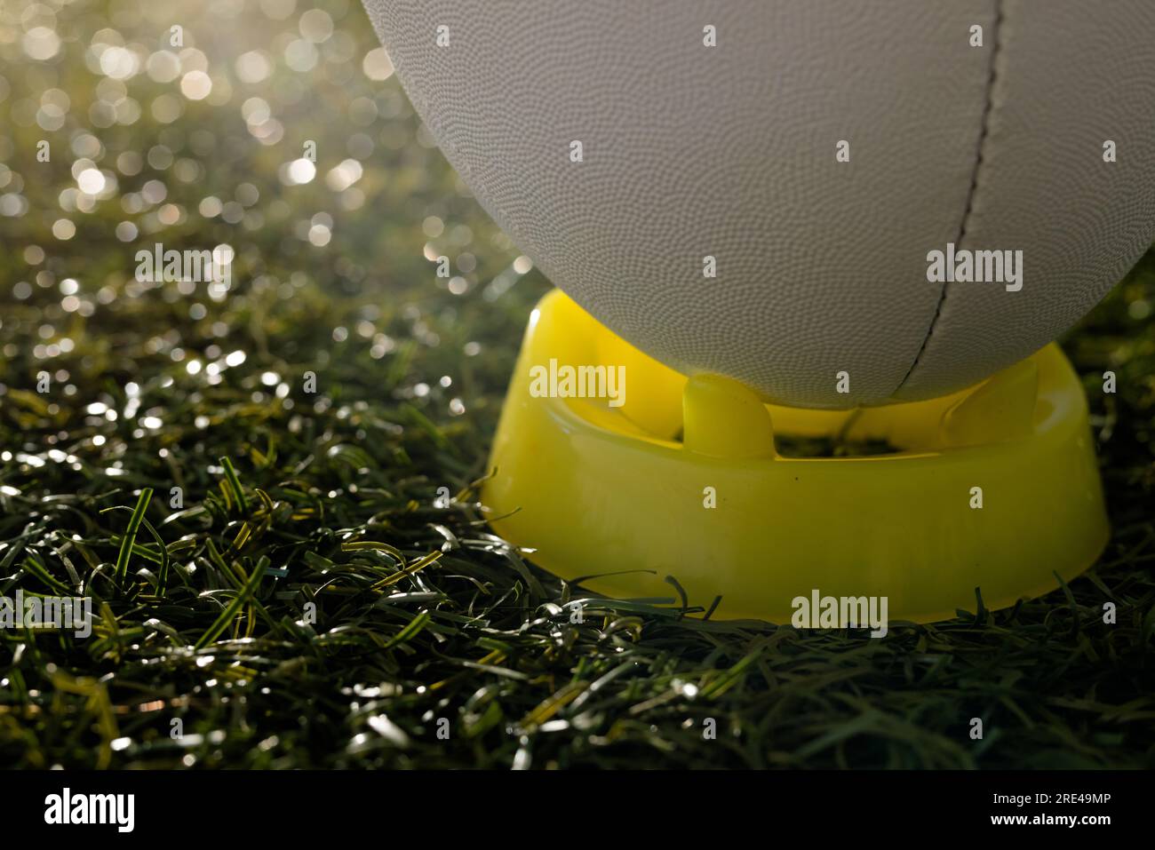 White rugby ball in yellow stand over grass with copy space, in slow ...