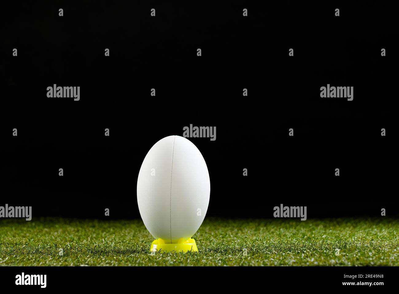 White rugby ball in yellow stand over grass with copy space, in slow ...