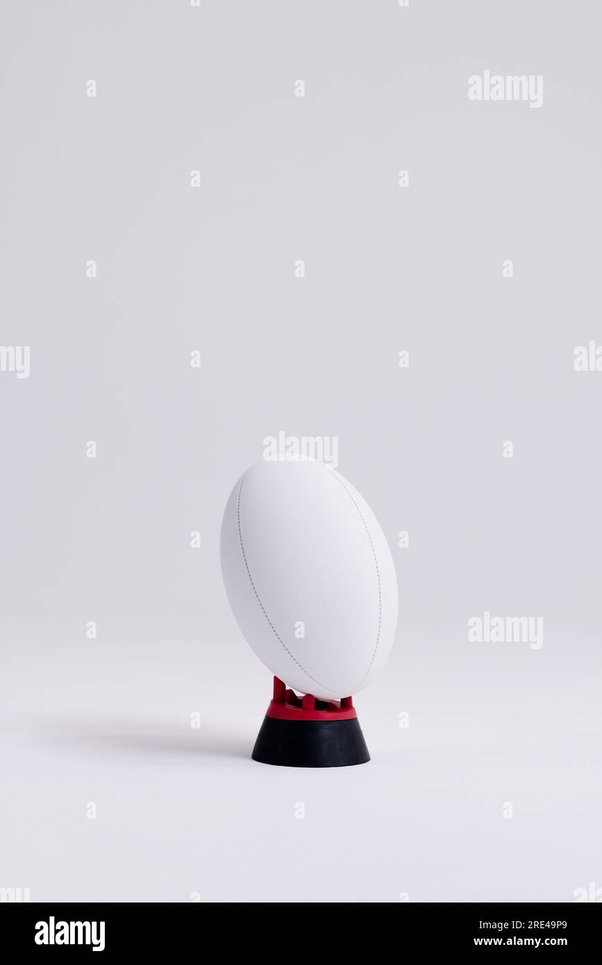 White rugby ball on red and black stand with copy space on white ...