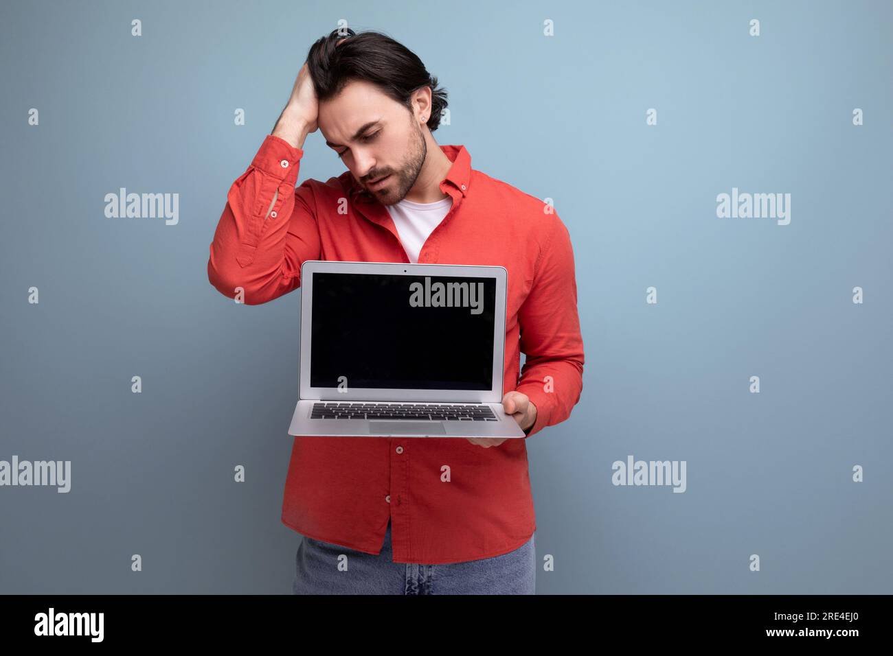 handsome young brunette man showing advertisement on screen with mockup ...