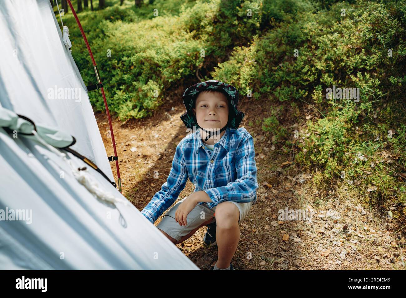 cute caucasian boy putting up a tent. Family camping conceptsunset shadows from trees. Family ...