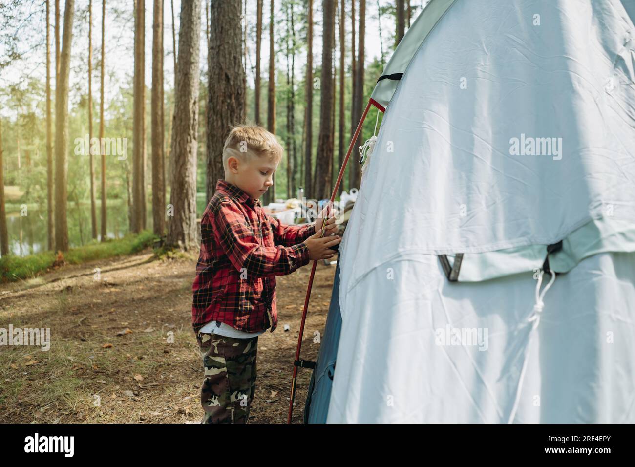 cute little caucasian boy putting up a tent. Family camping concept. Image with selective focus ...