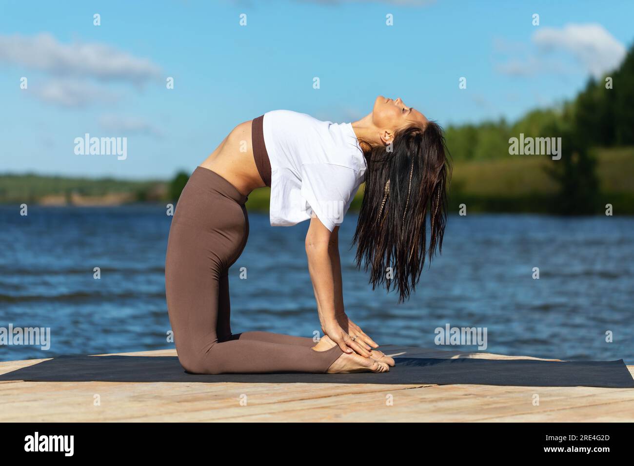 A woman practicing yoga, performs the Ushtrasana exercise, camel pose ...