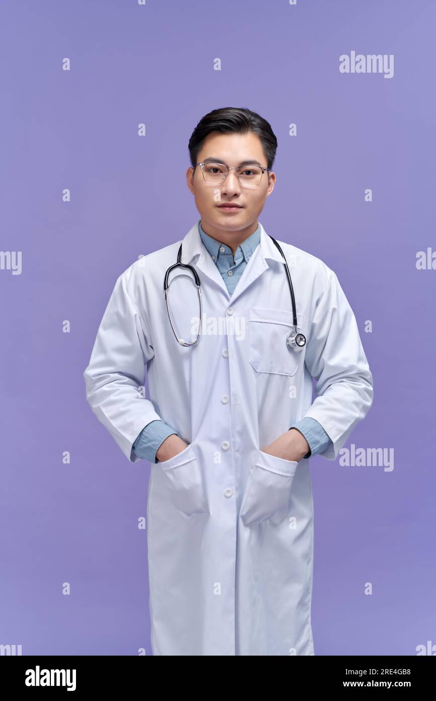 Portrait of male confident doctor over purple background studio ...