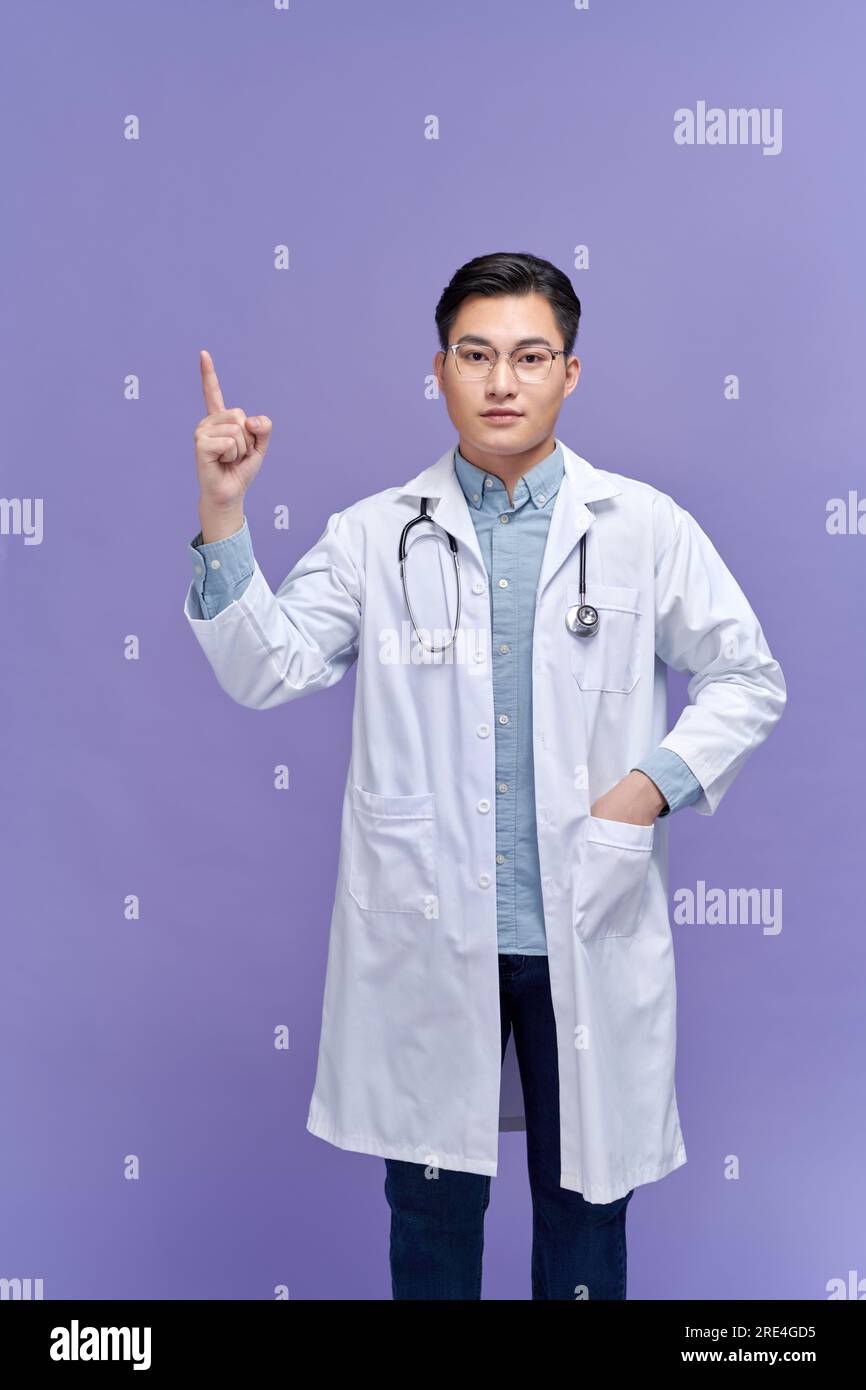 Male doctor makes a pointing finger gesture, isolated over a purple ...