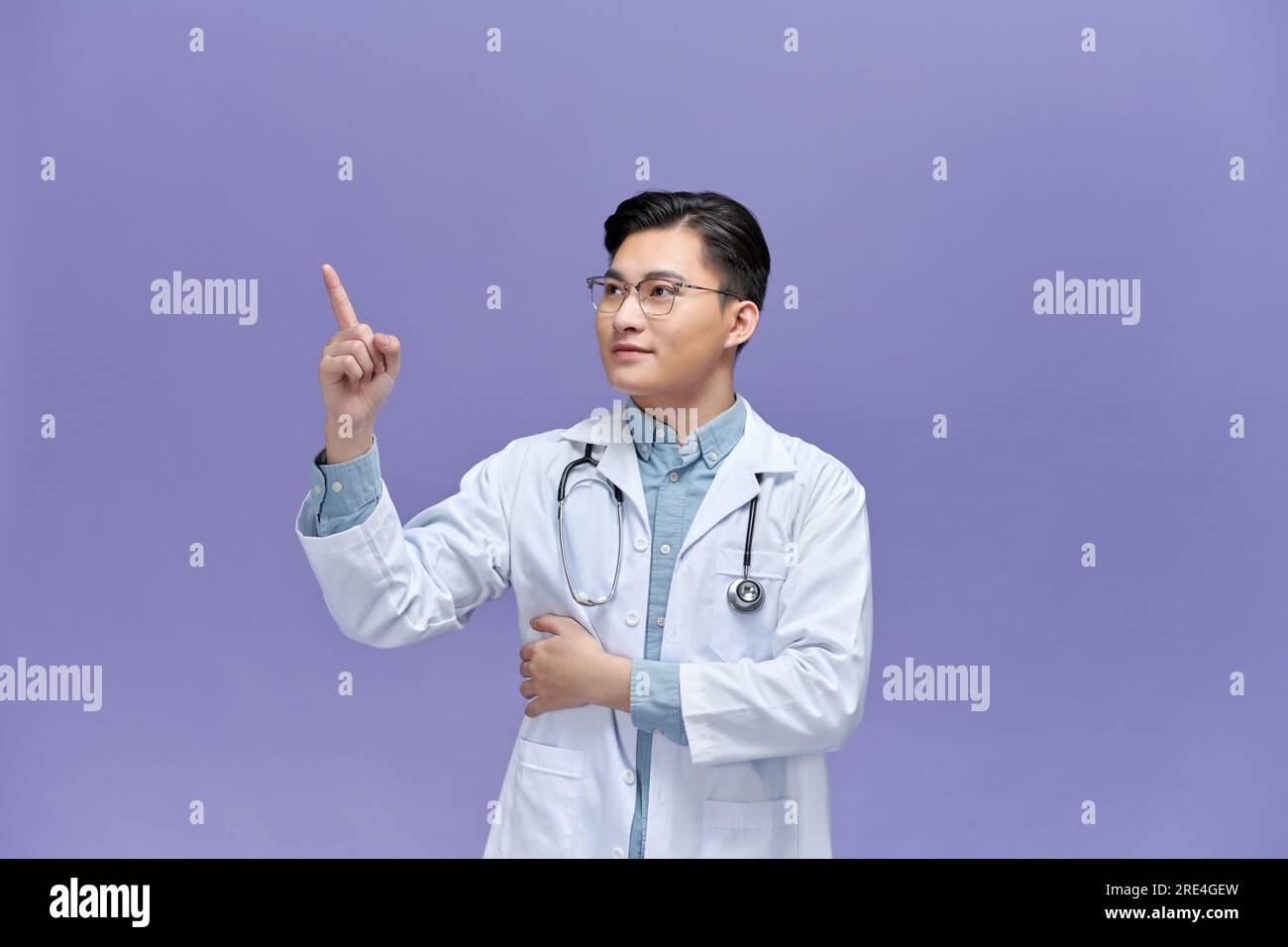 portrait of friendly doctor pointing up studio isolated; male doctor ...