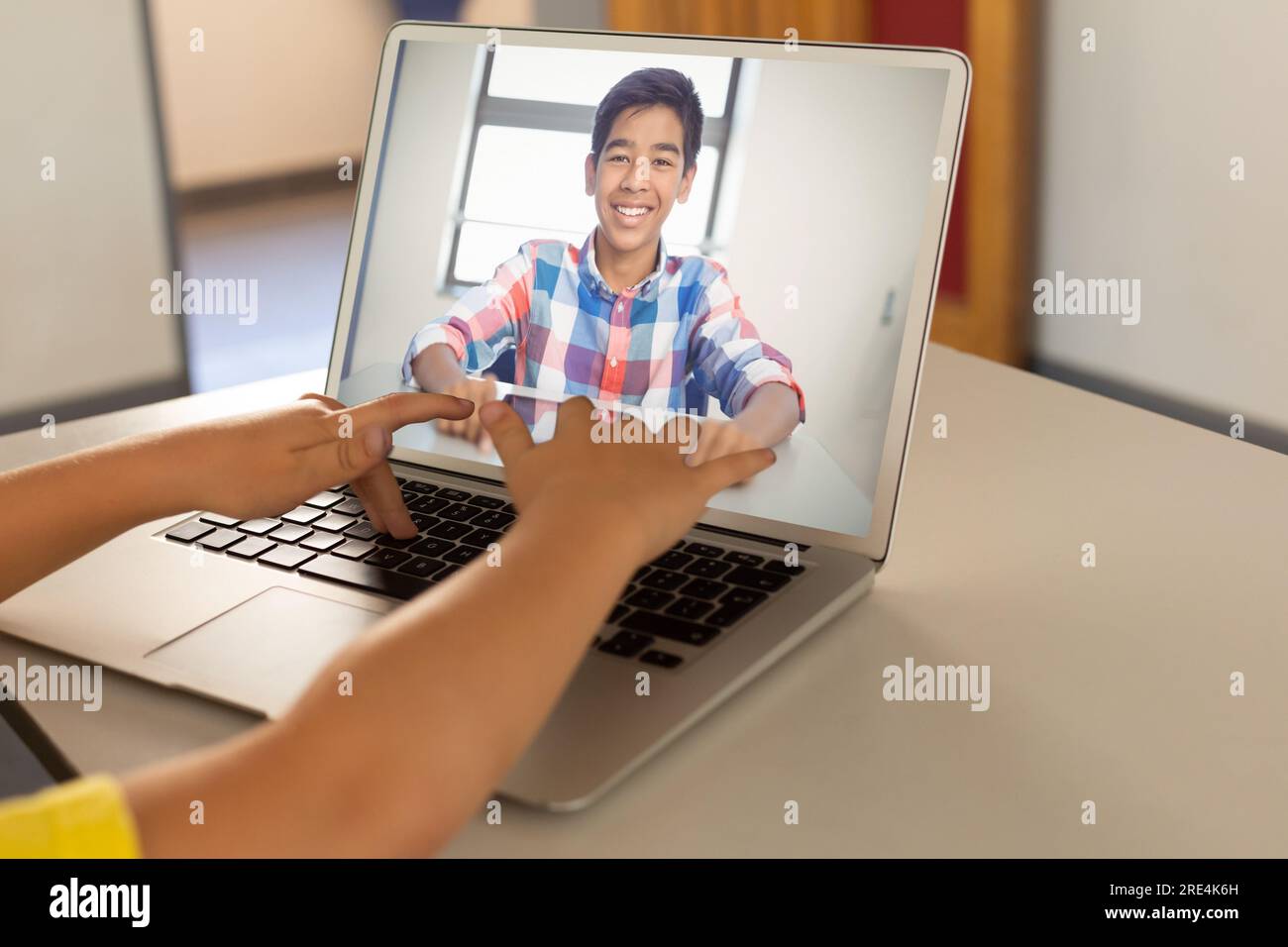 Mid section of a boy using laptop while having a video call with indian ...