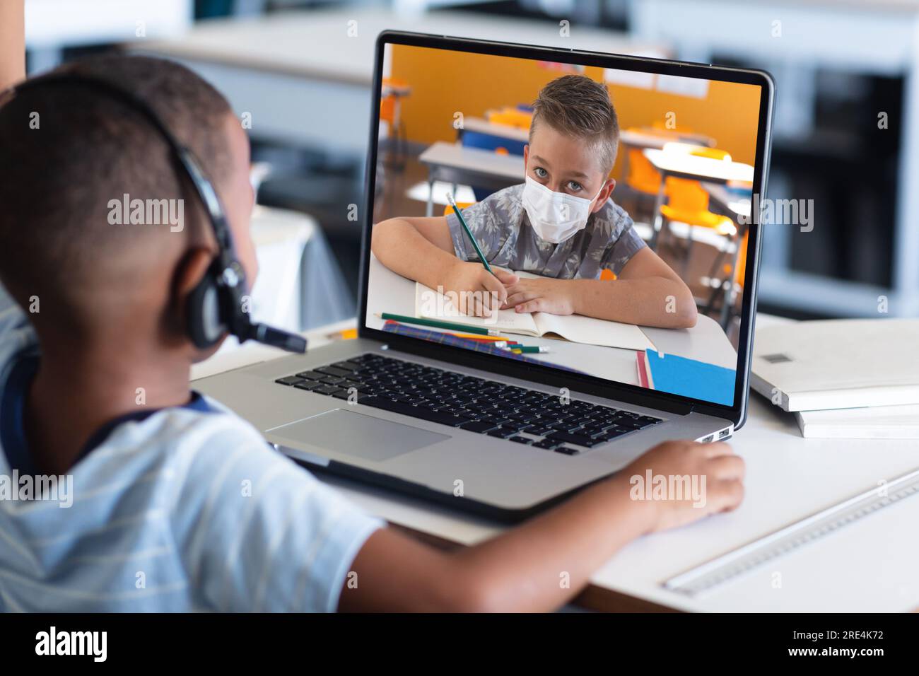 Rear view of african american boy using laptop while having a video call with caucasian boy at ...