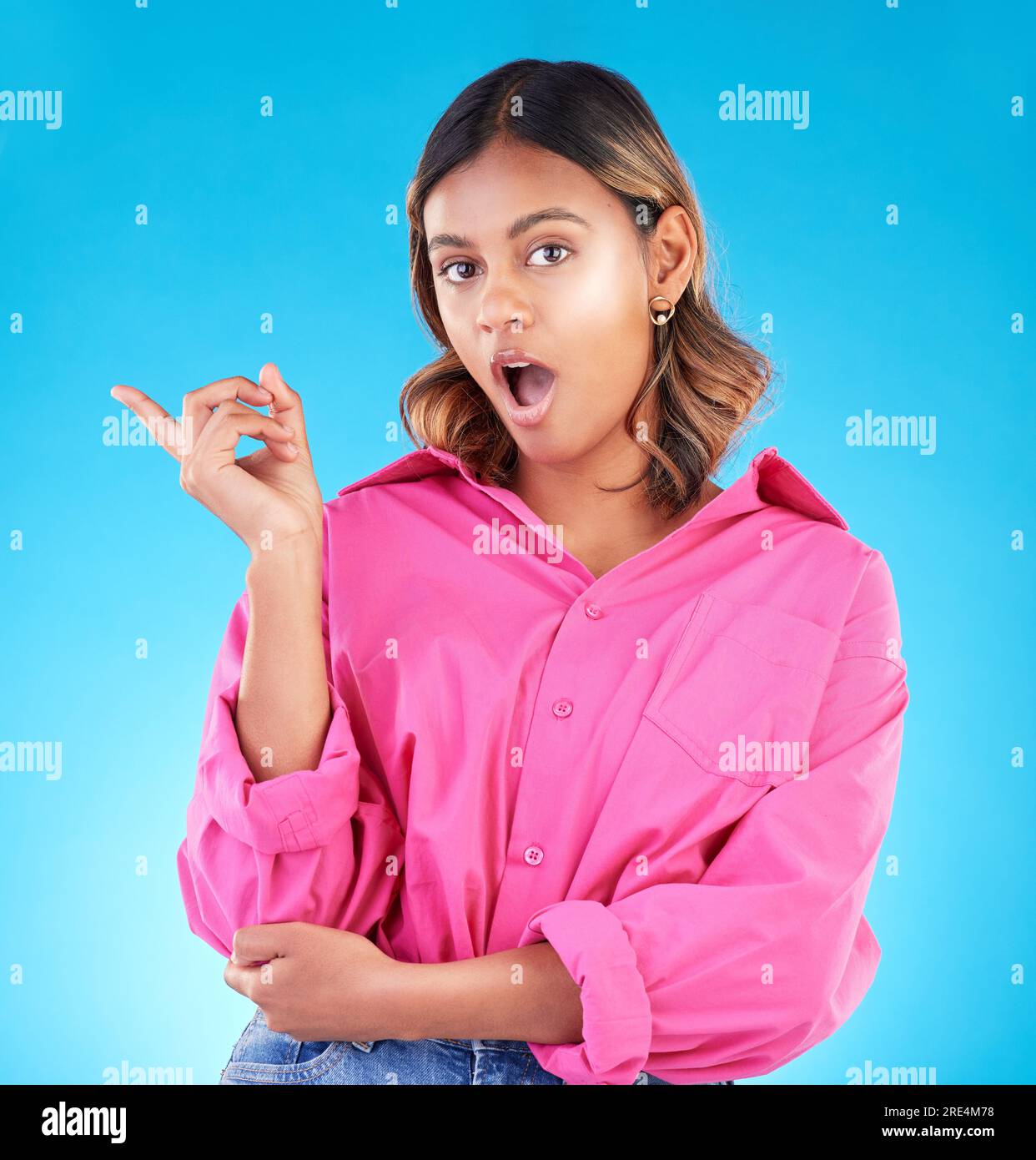 Surprise, pointing and space with portrait of woman in studio for news ...