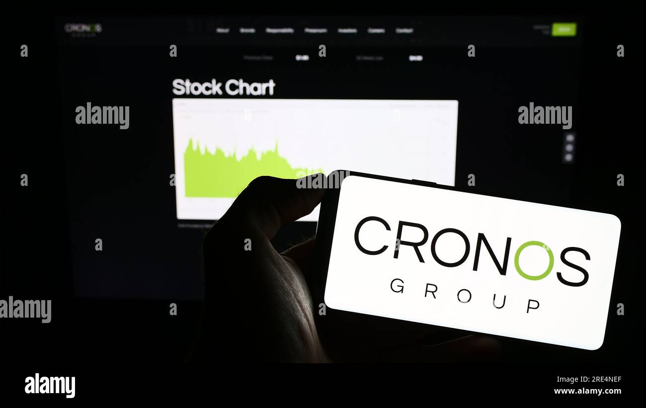 Person holding cellphone with logo of Canadian cannabis company Cronos ...