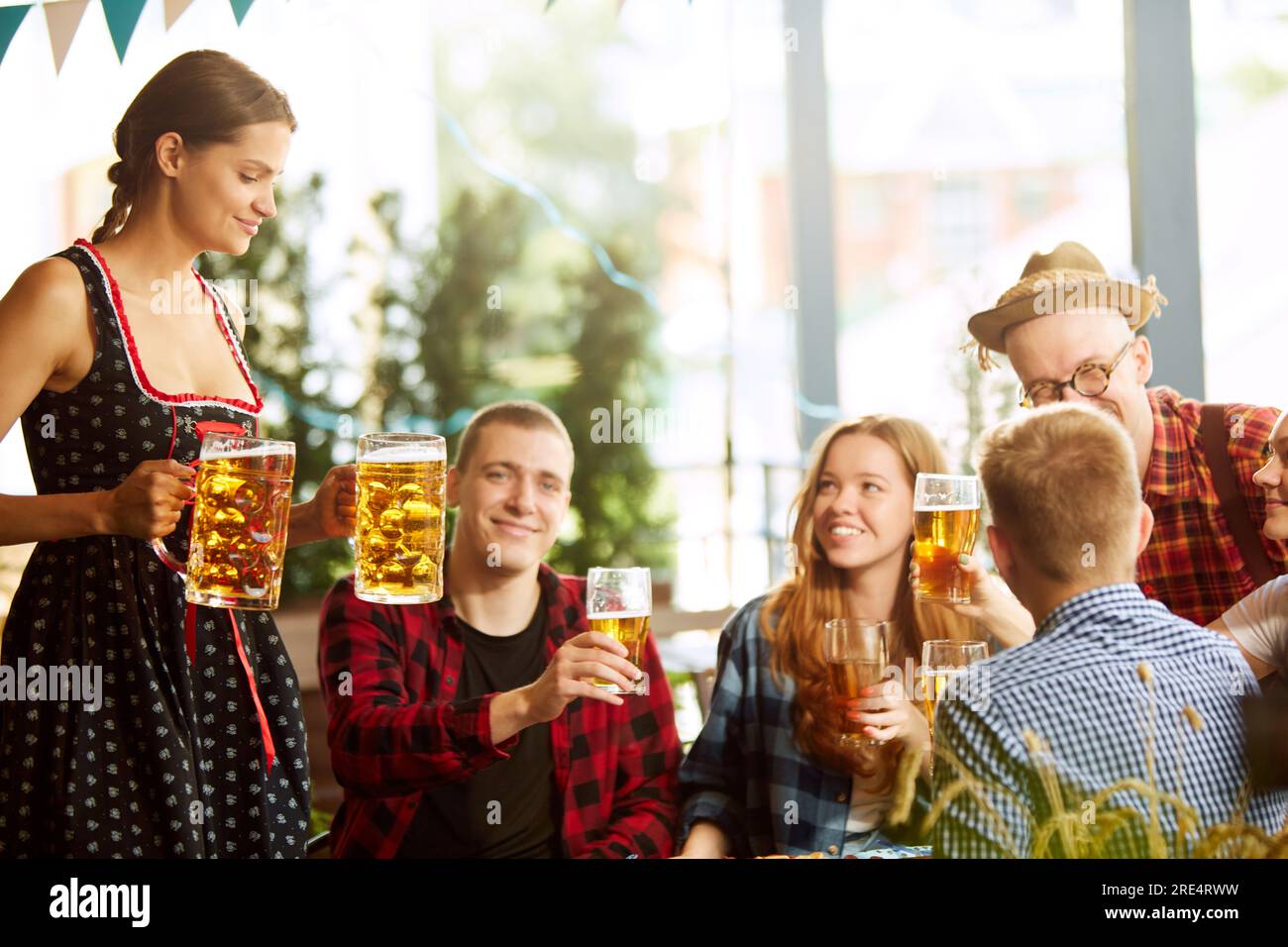 Beautiful young woman, waitress serving big mugs with lager beer to ...