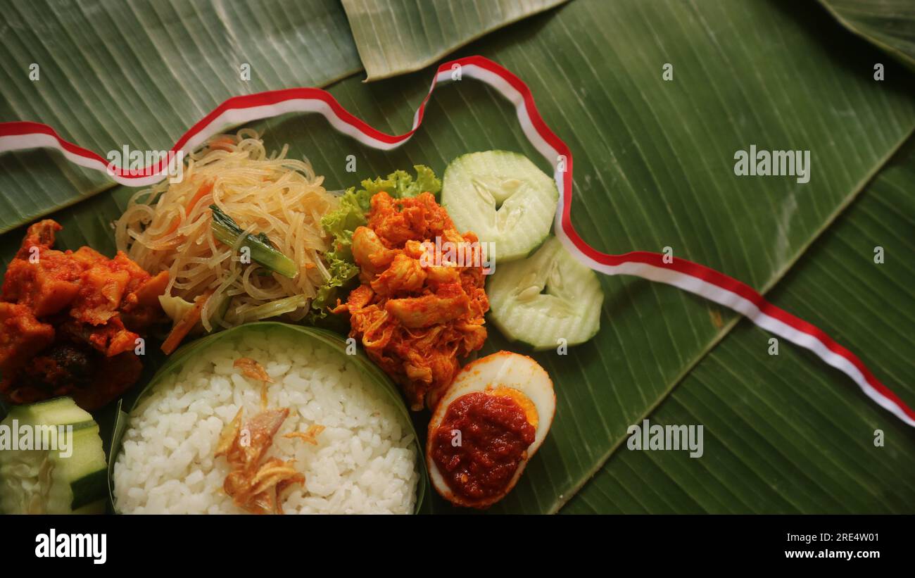 Savory rice, noodles, cucumber, seasoned potatoes on a banana leaf ...