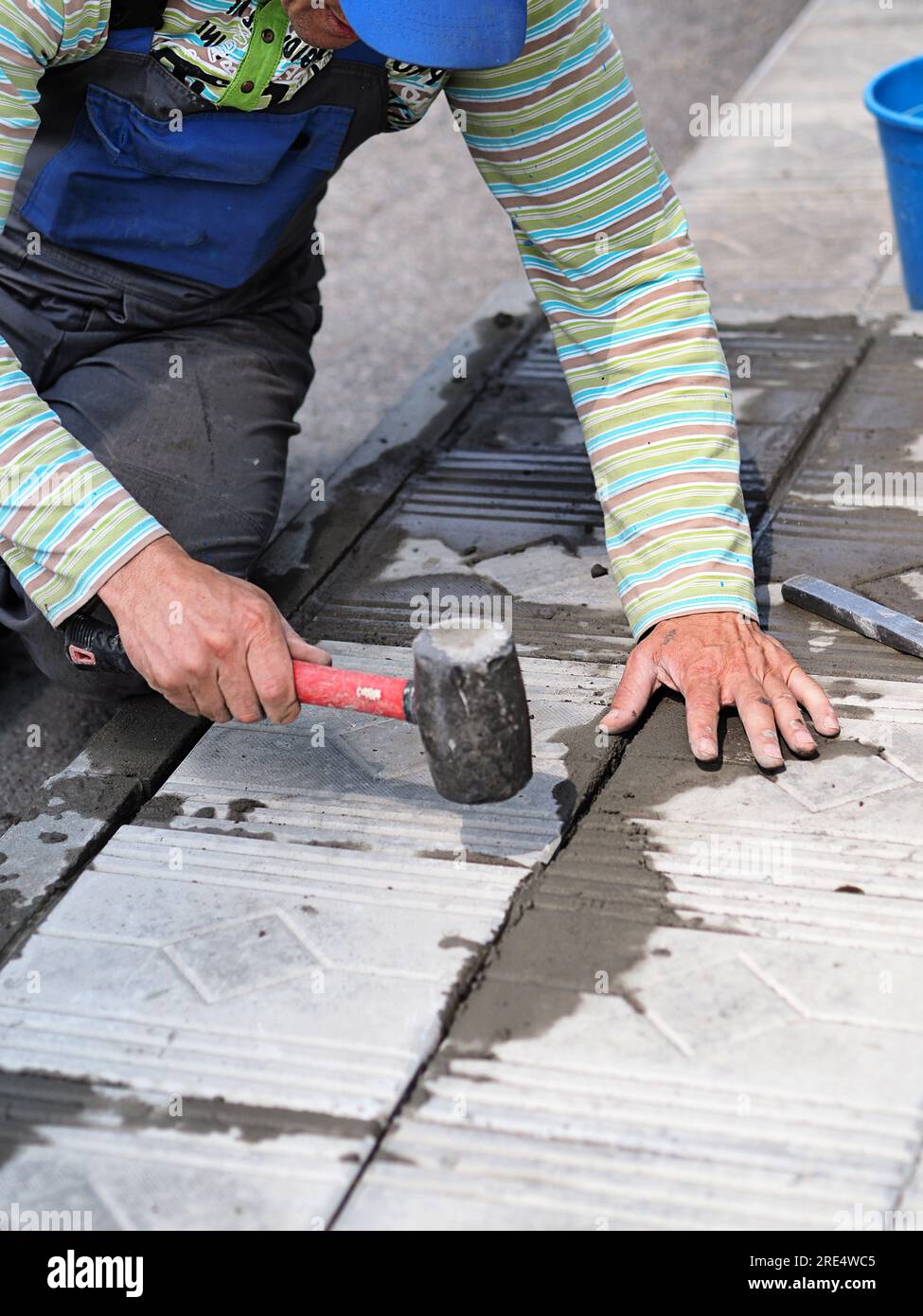 Tiler worker laying tiles on foundation of building outside. Hands of ...