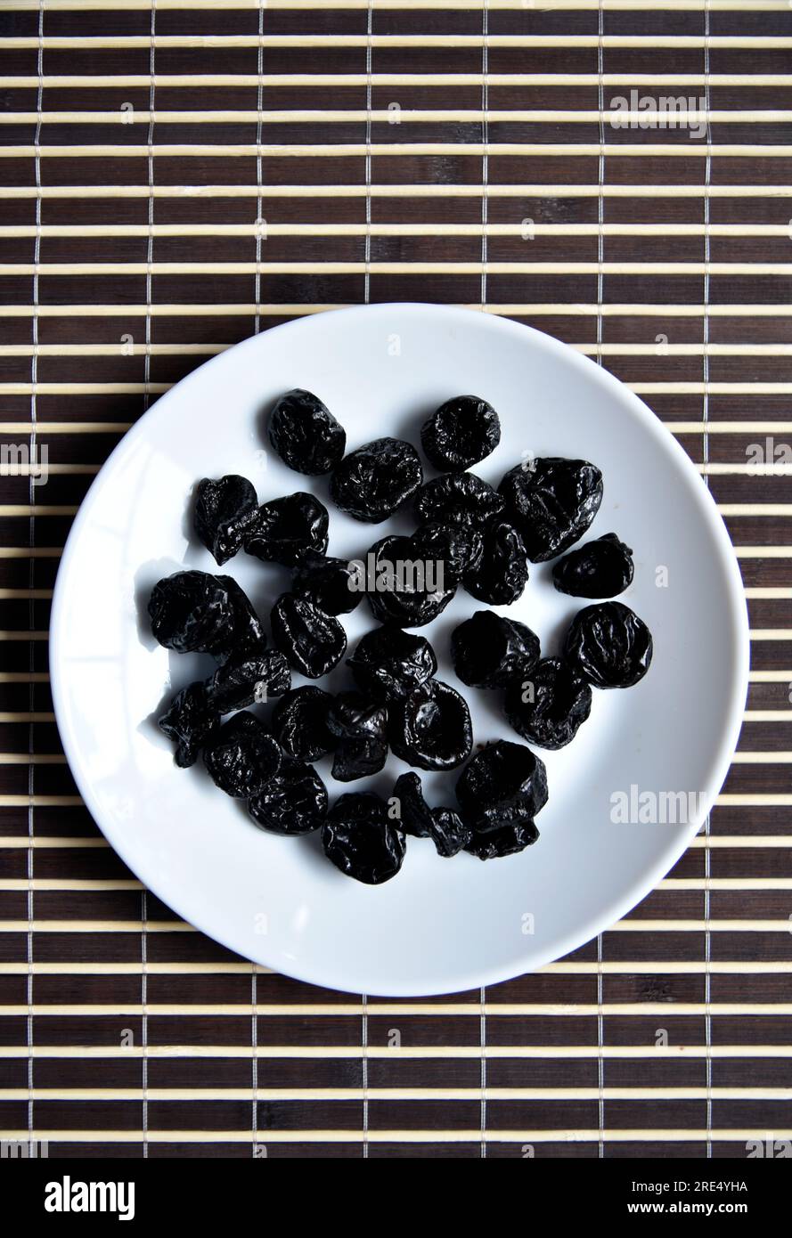 Dried prunes on a white plate close-up. Healthy eating. Delicious taste ...