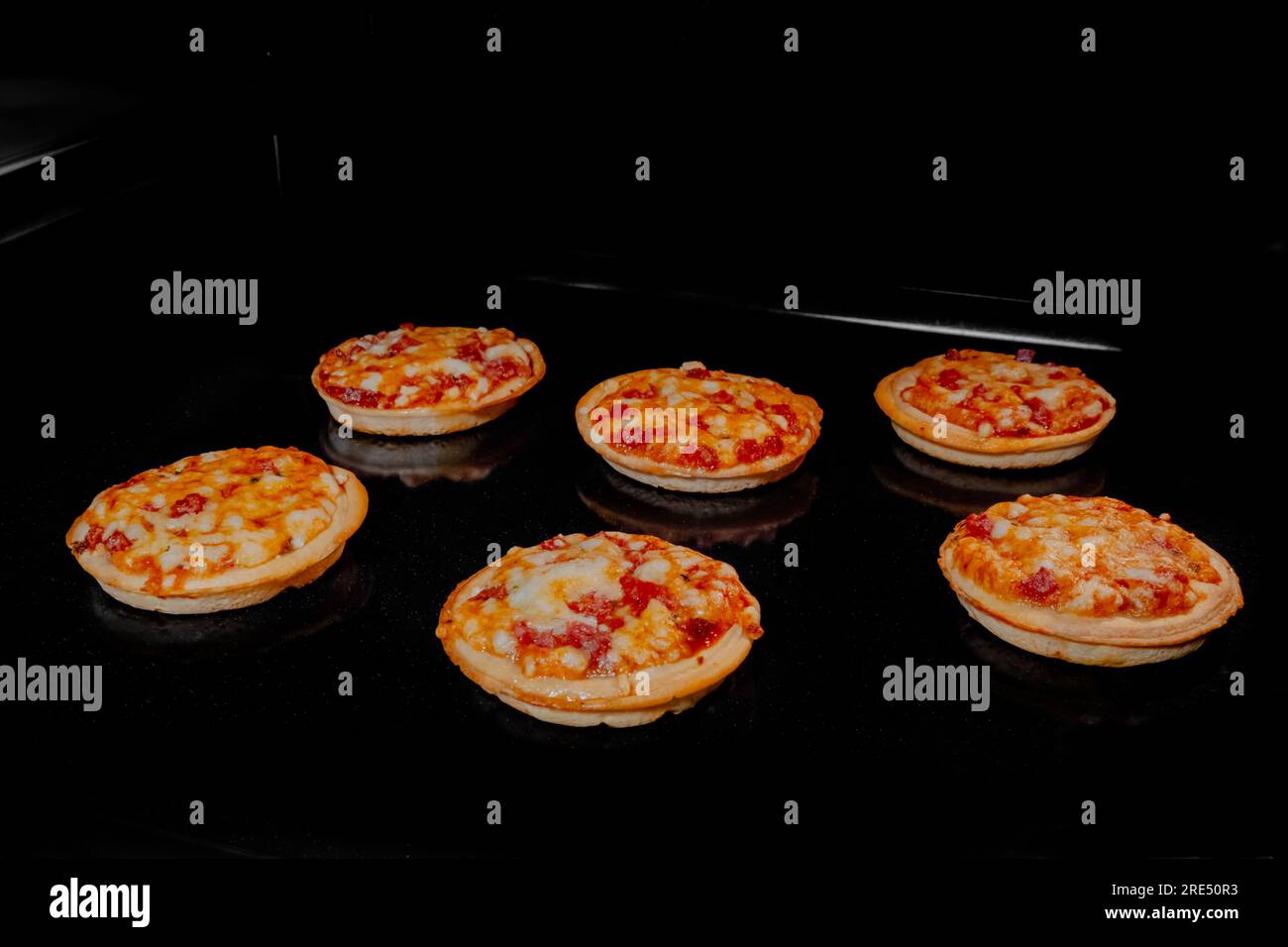 Six baked homemade mini pizzas in electric oven at home, black background Stock Photo - Alamy