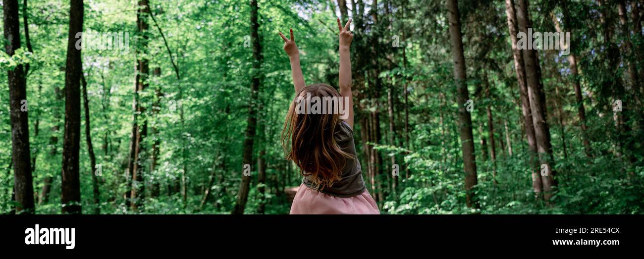 View from behind of a toddler girl standing in beautiful bright green ...