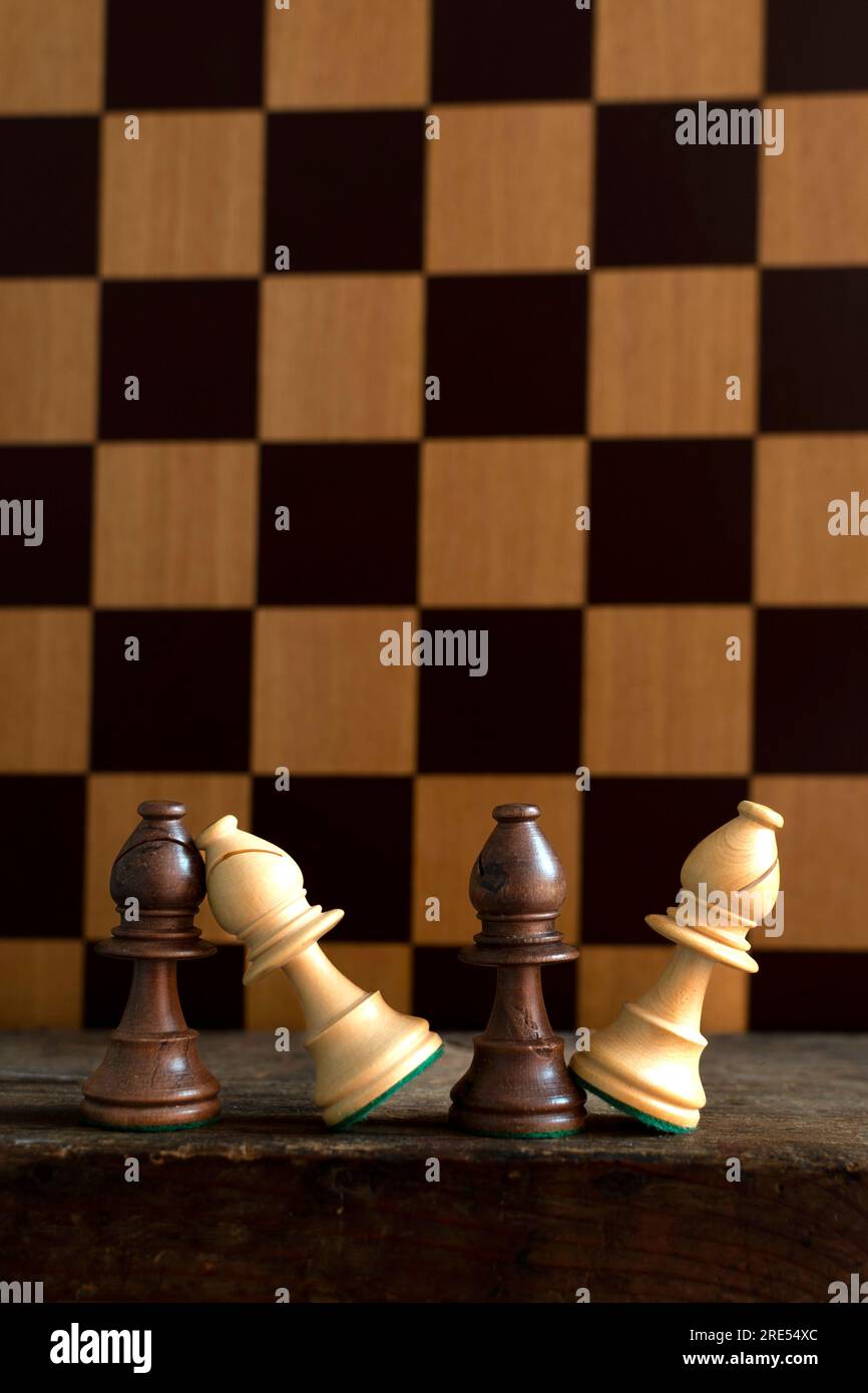 Chess pieces stand elegantly on a wooden table with a checkered board ...