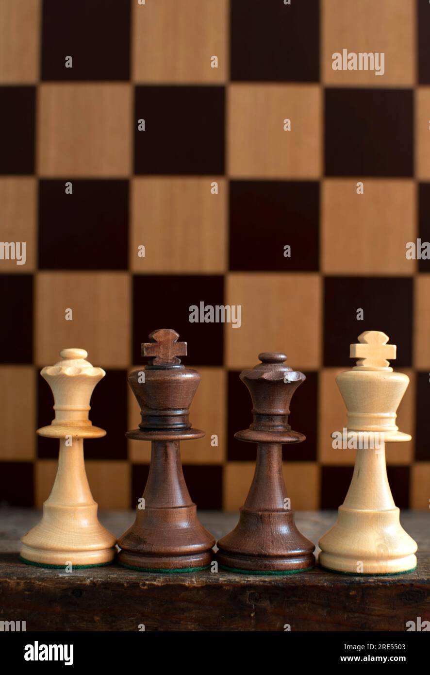 Chess pieces stand elegantly on a wooden table with a checkered board ...