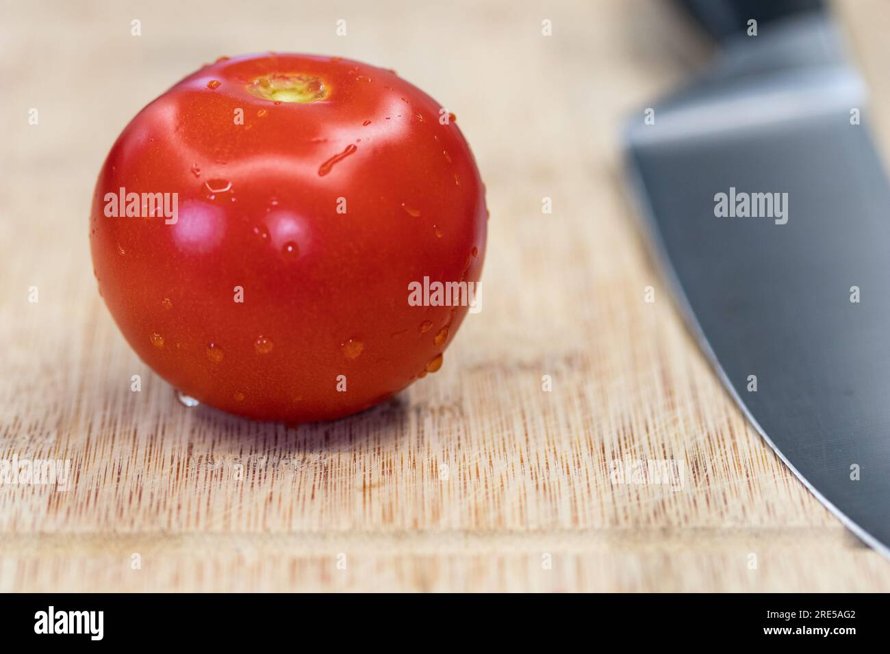 Chopping tomato on wooden table. Red round lucid tomato with metal ...