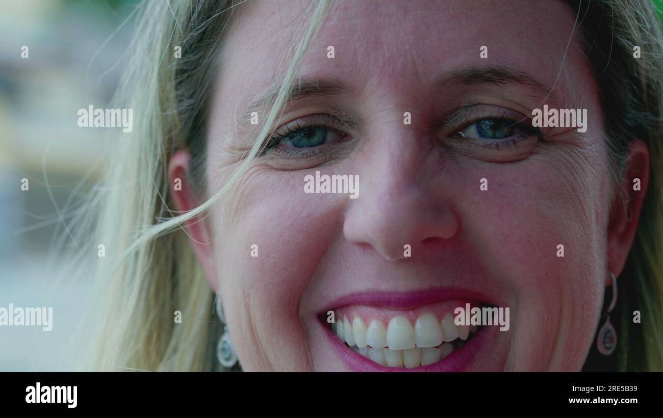 Macro close-up face of a happy woman in mid 40s smiling at camera. One ...