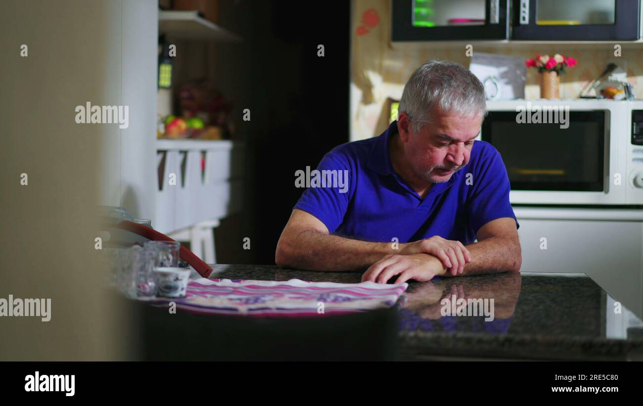 Preoccupied senior man at kitchen table ruminating problems, candid ...