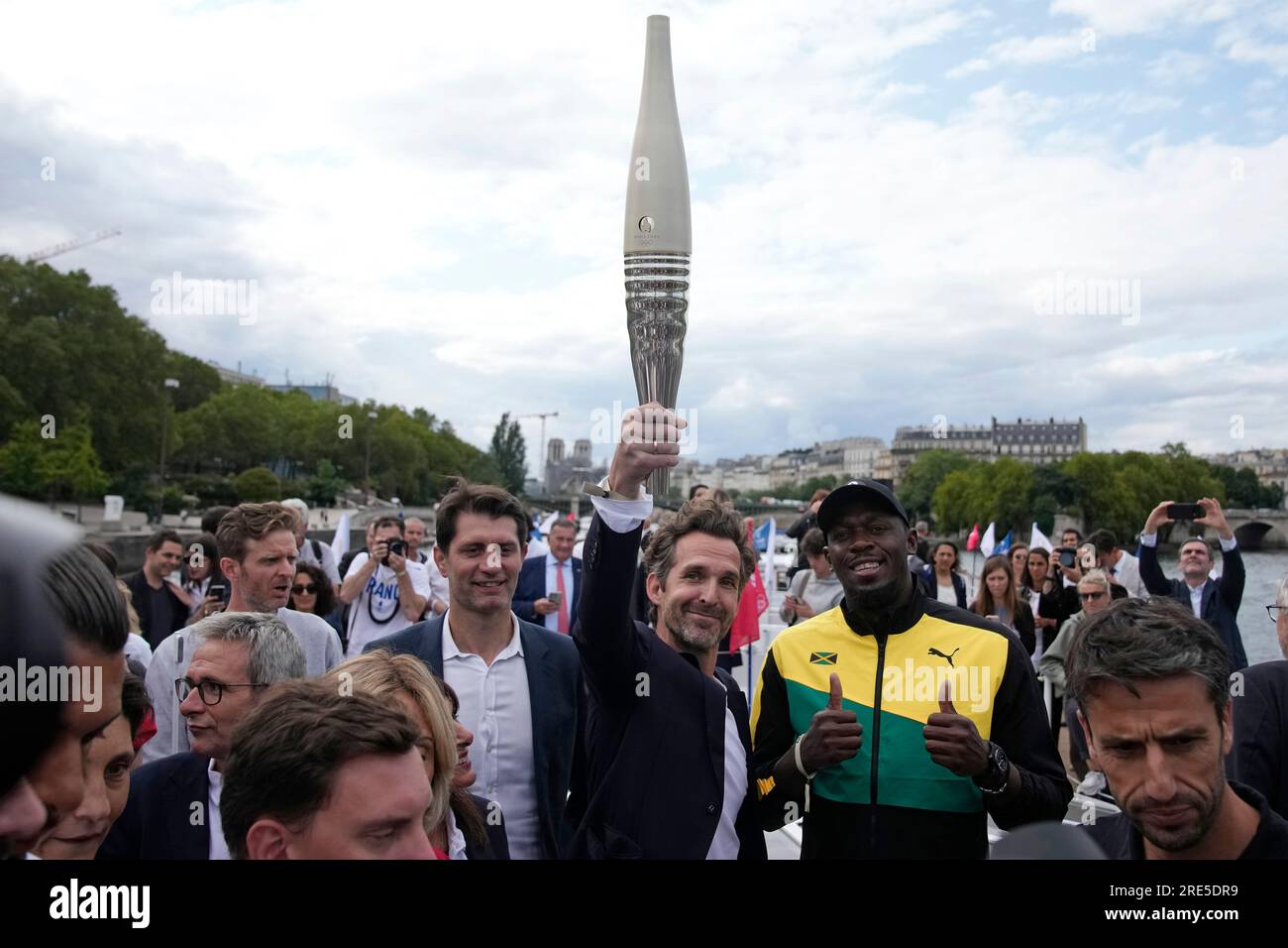 French designer Mathieu Lehanneur holds the Olympic torch as former ...