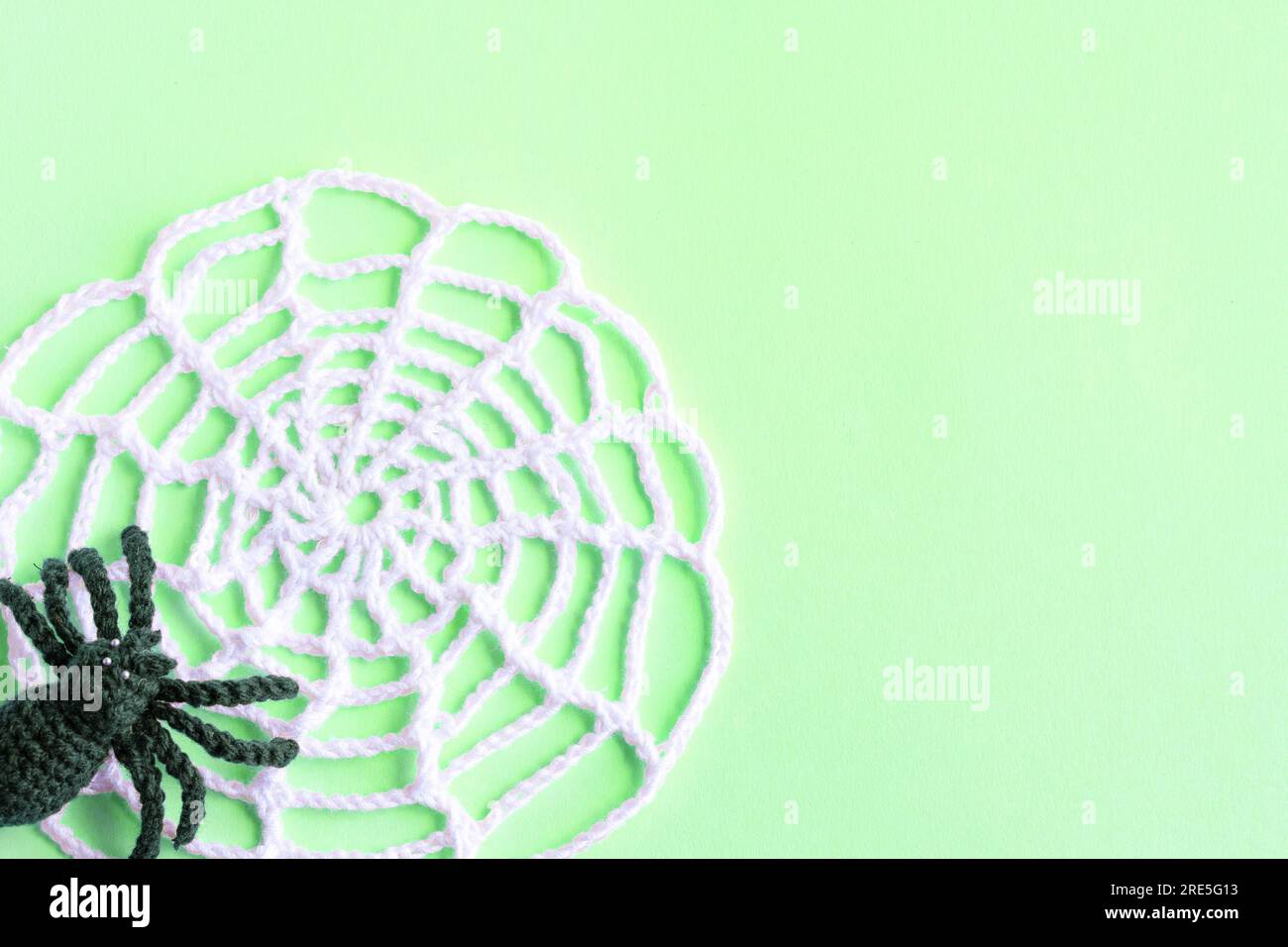 Halloween concept. Knitted spider and white web on an green background ...