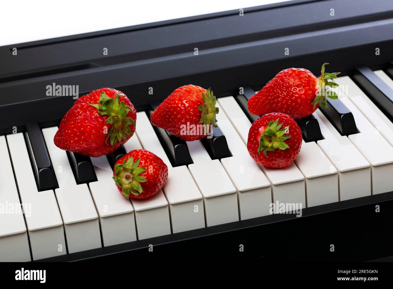 Five ripe strawberries on the piano keys Stock Photo - Alamy