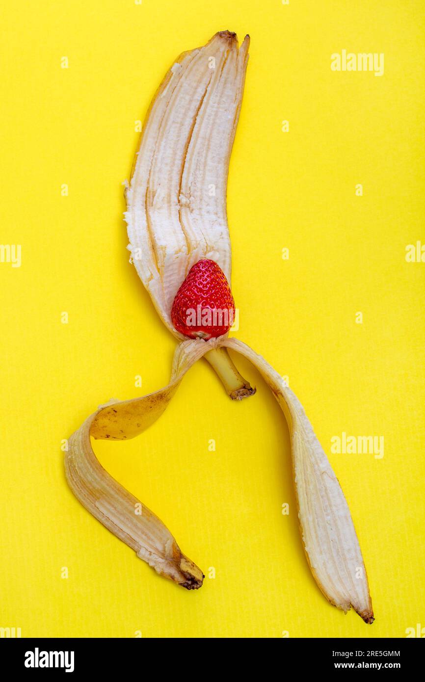 The peel of a ripe banana with a strawberry berry on a yellow ...
