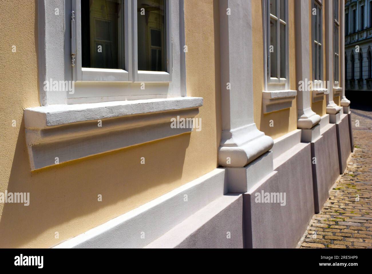 Yellow stucco house elevation closeup with wood windows, sills and ...