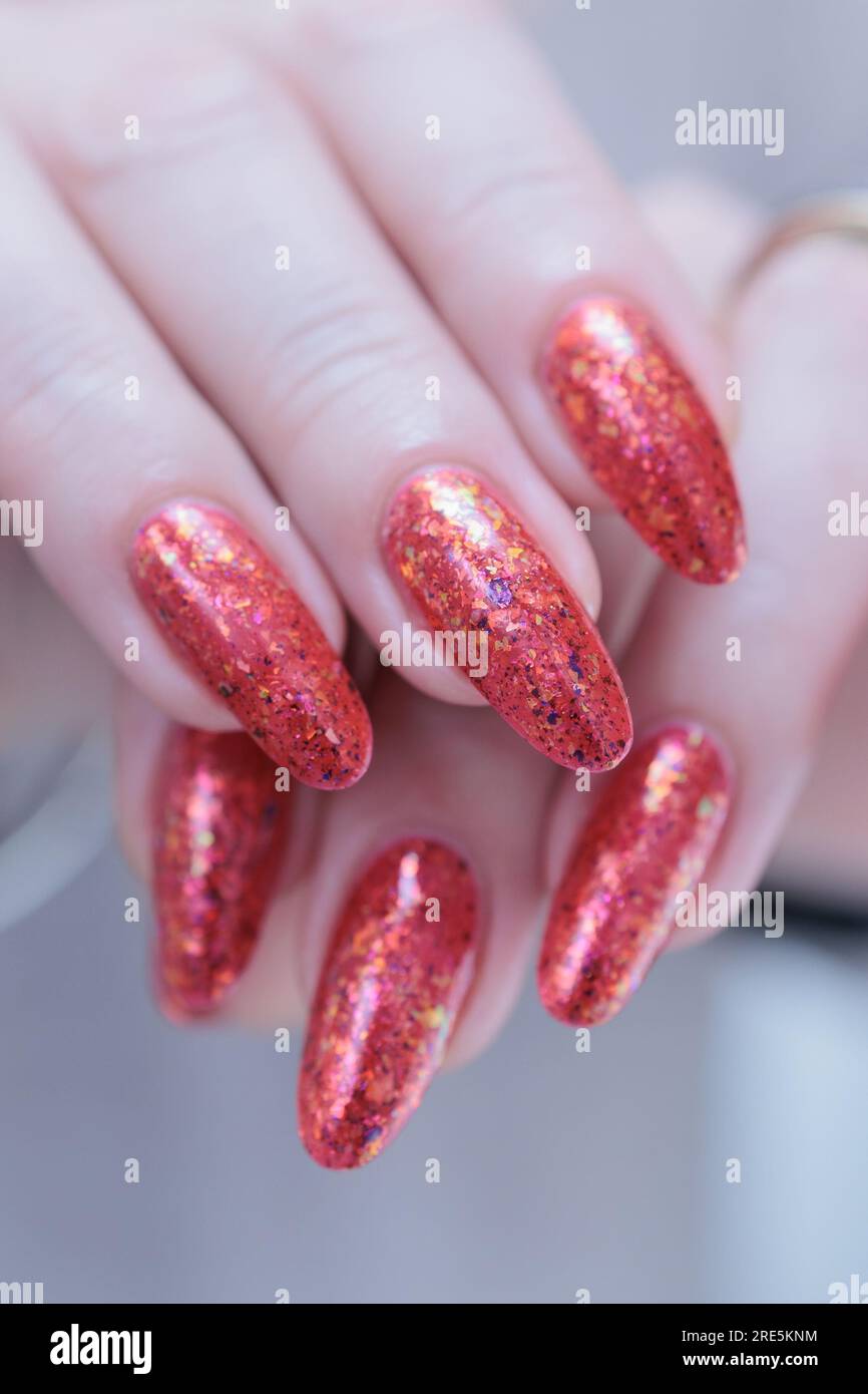 Female beautiful hand with long nails and a bright orange red nail ...