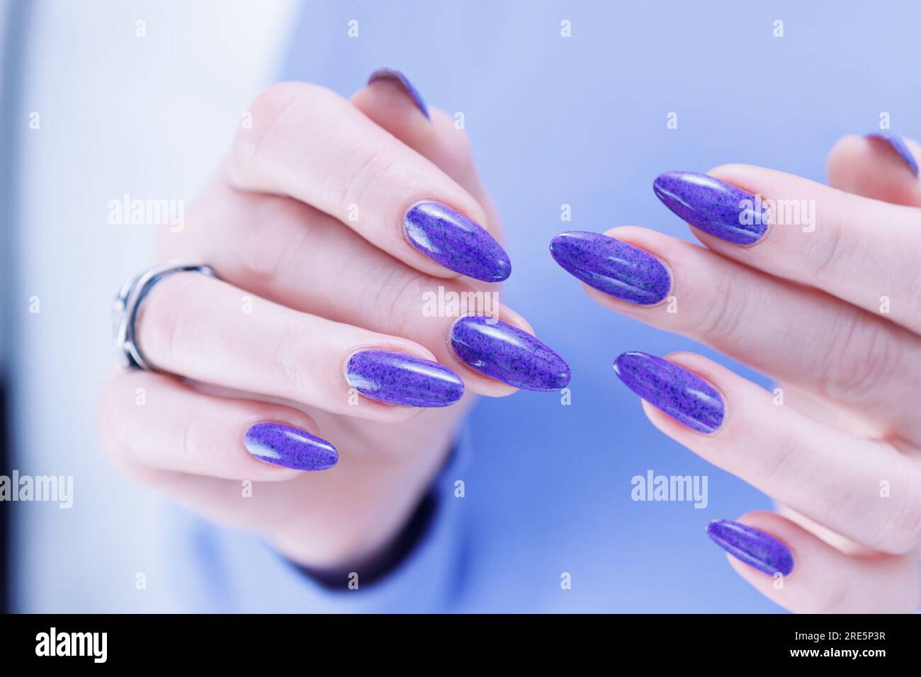 Female hand with long nails and a light blue lilac color nail polish ...