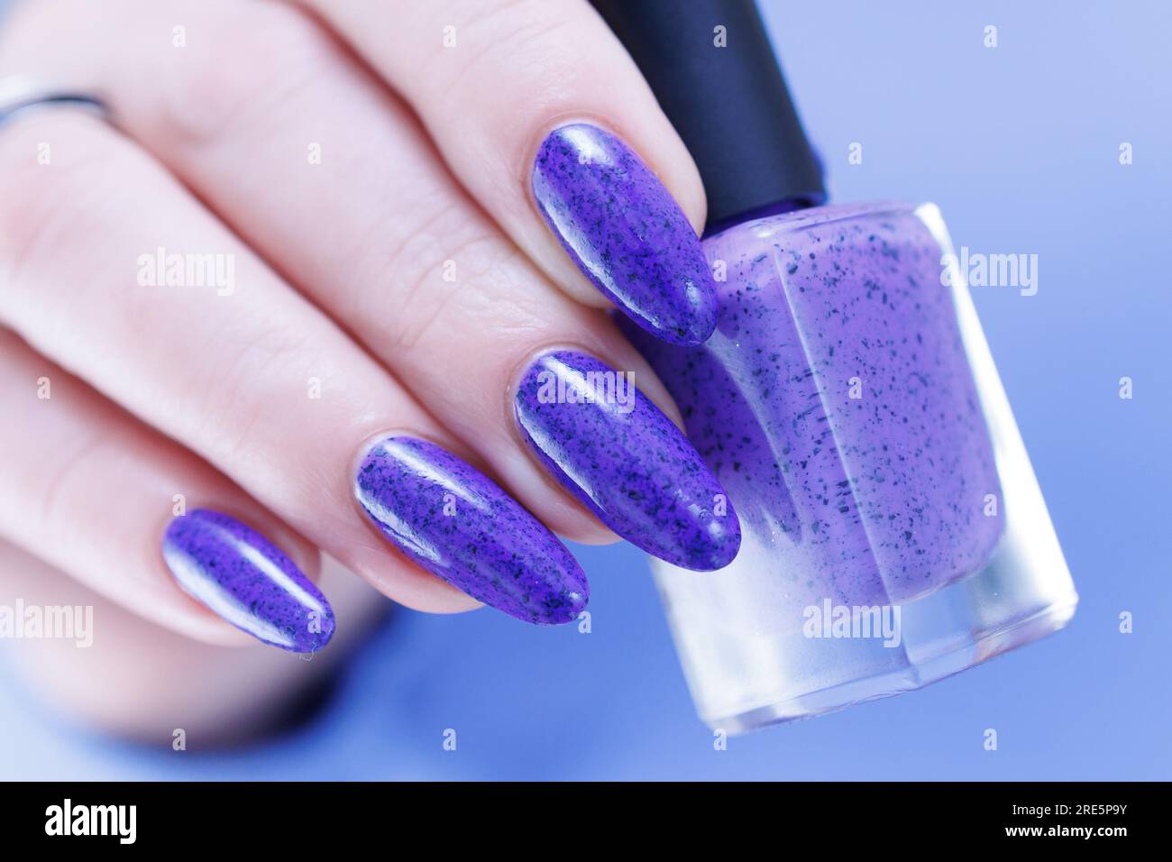 Female hand with long nails and a light blue lilac color nail polish ...