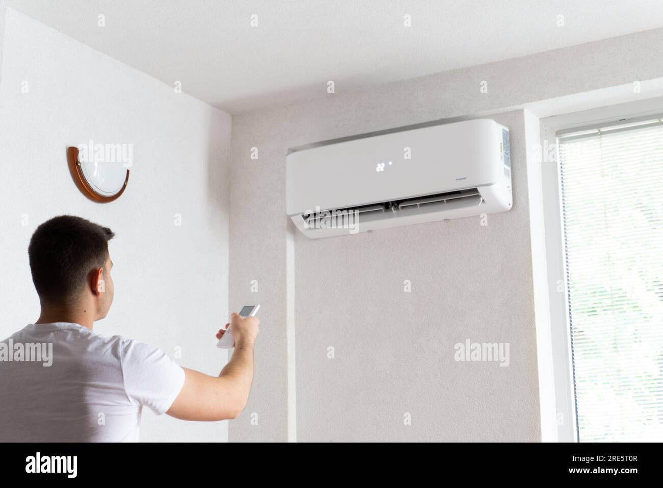 Young man switches air conditioning on. Handsome young man turning on ...