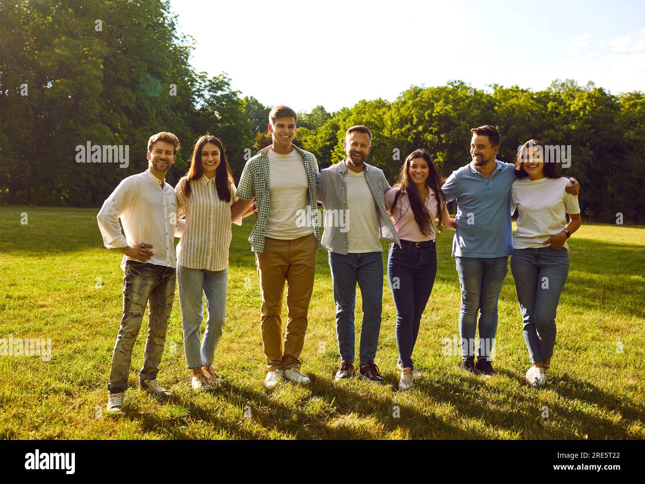 Group of happy young friends huddling and having fun in a green park in ...