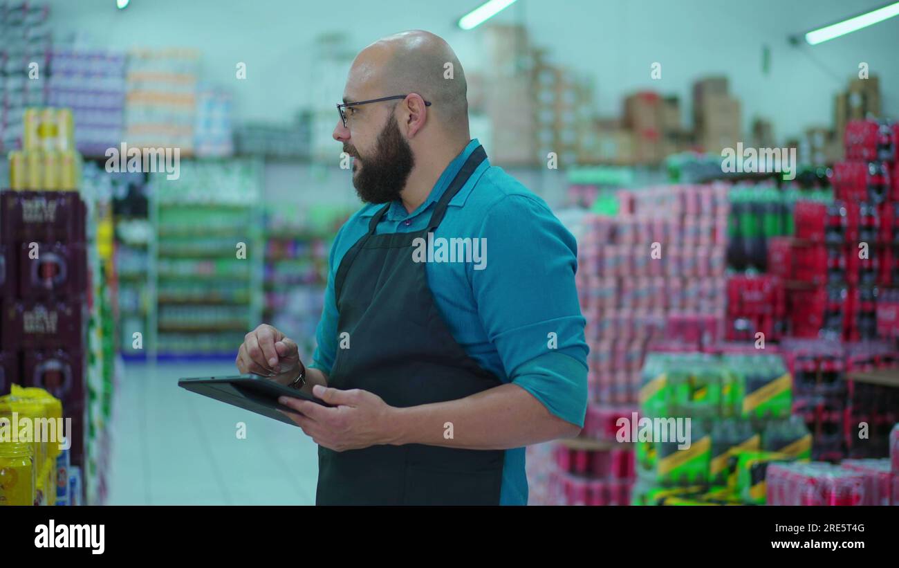 Supermarket staff browsing product inventory with tablet device. Male ...
