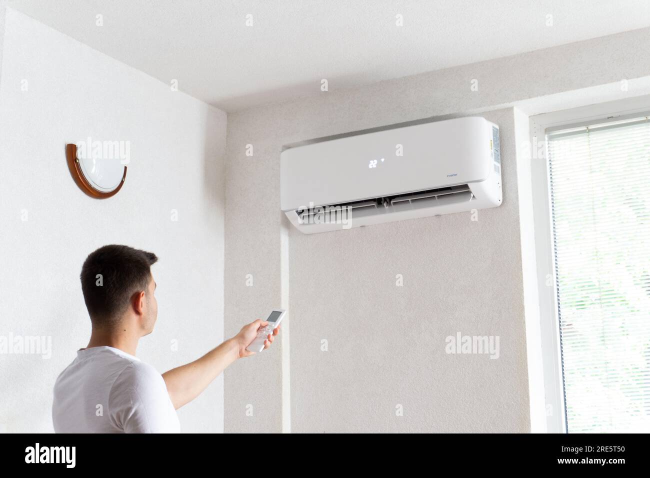 Young man switches air conditioning on. Handsome young man turning on ...