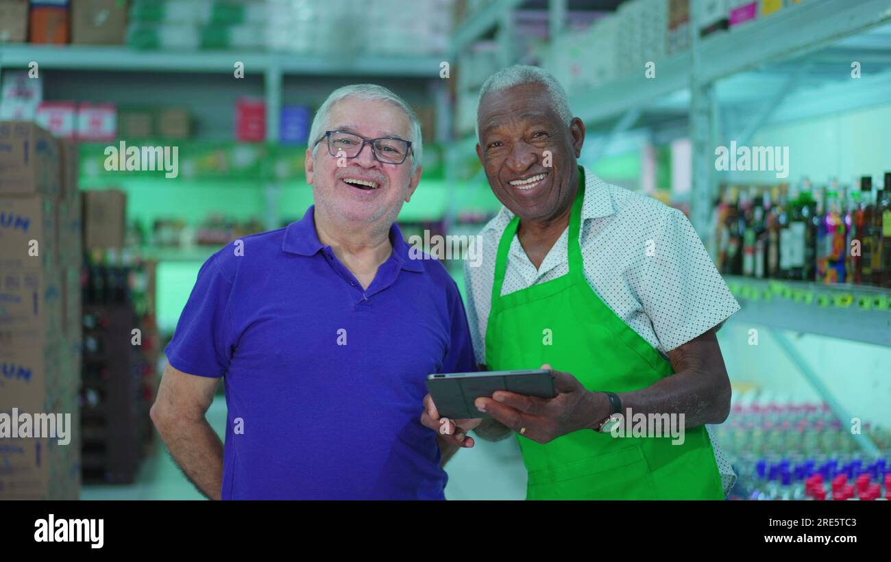Two senior employees of Grocery store posing for camera smiling inside ...