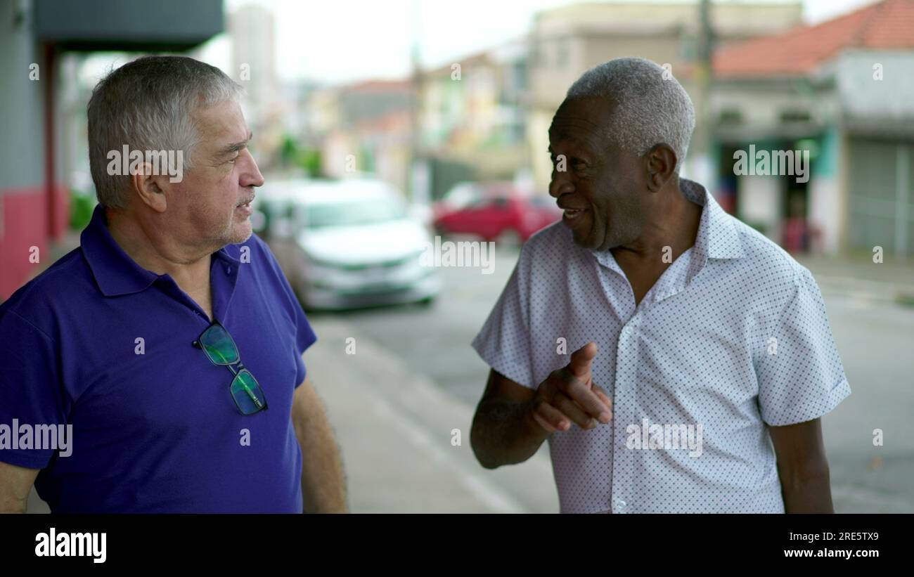 Seniors conversing while standing in city street, candid interaction ...
