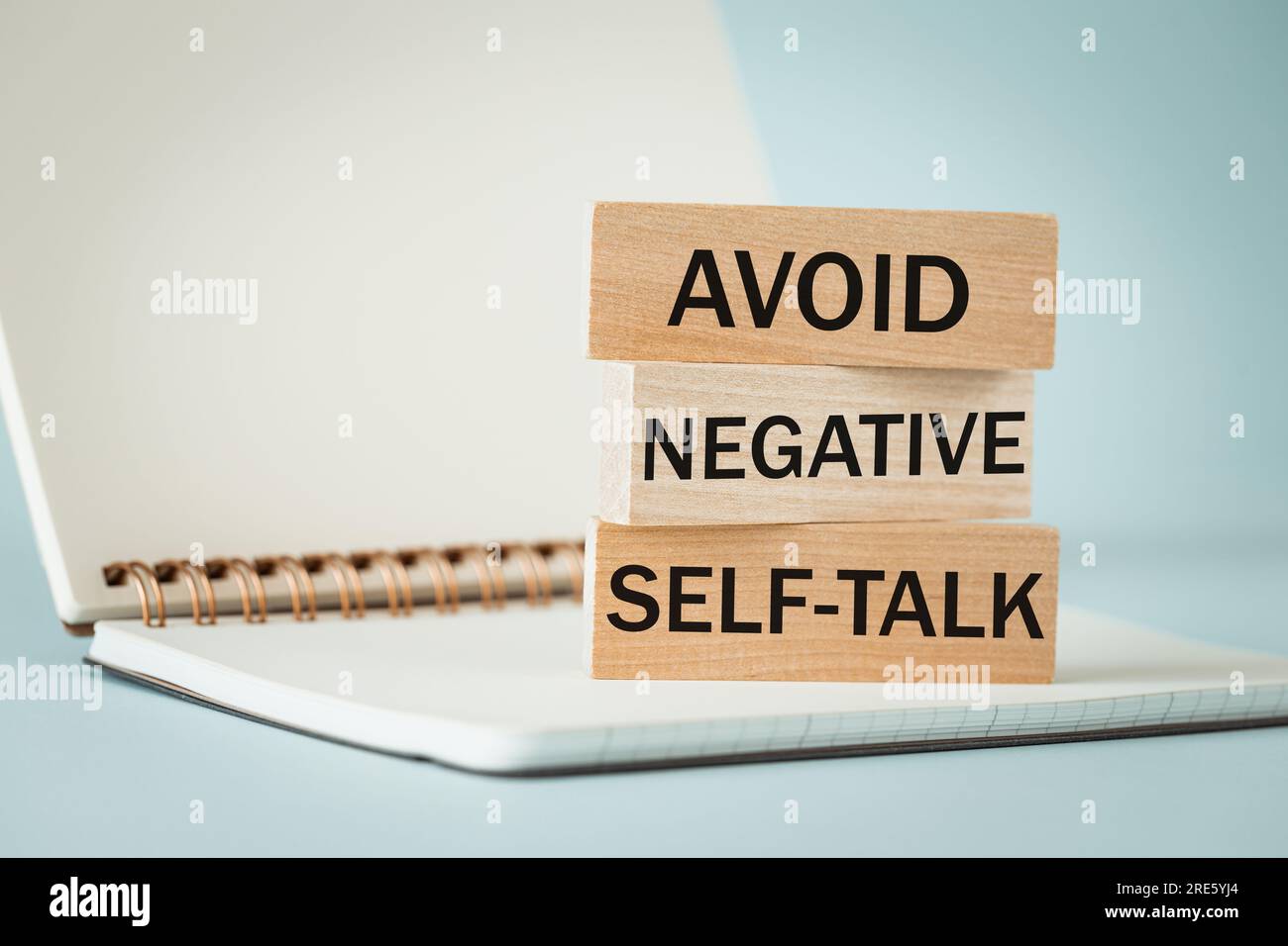 avoid negative self-talk written on wooden blocks standing on an open ...