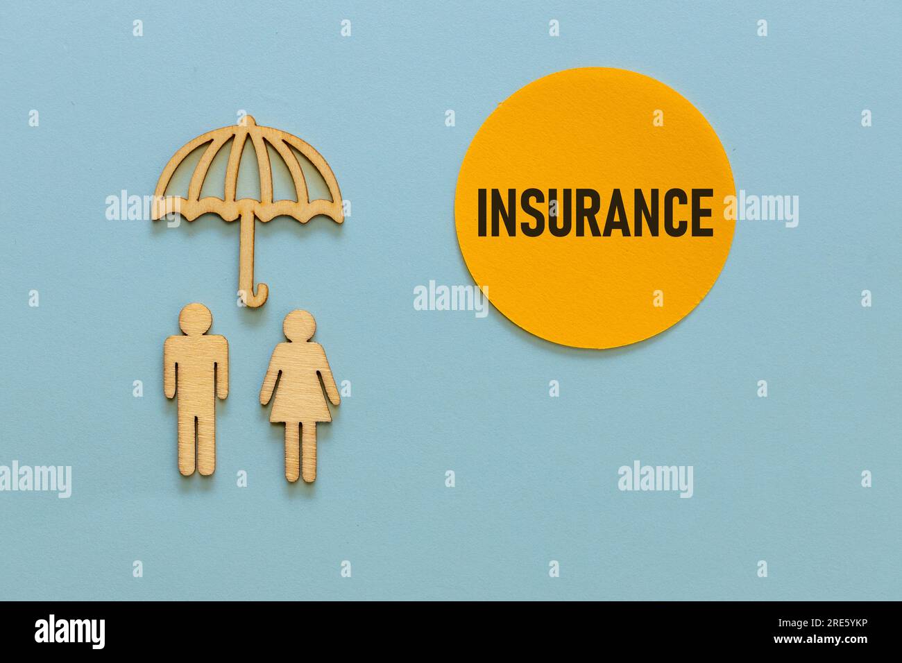 Wooden figures of people under an umbrella, Insurance text on a ...