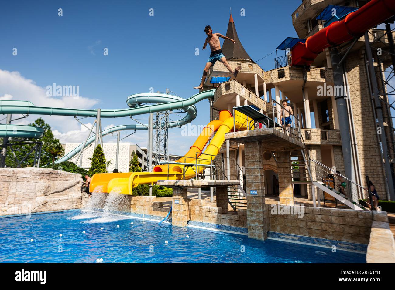 Boy jumping from trampoline at water slides at the theme aqua park ...